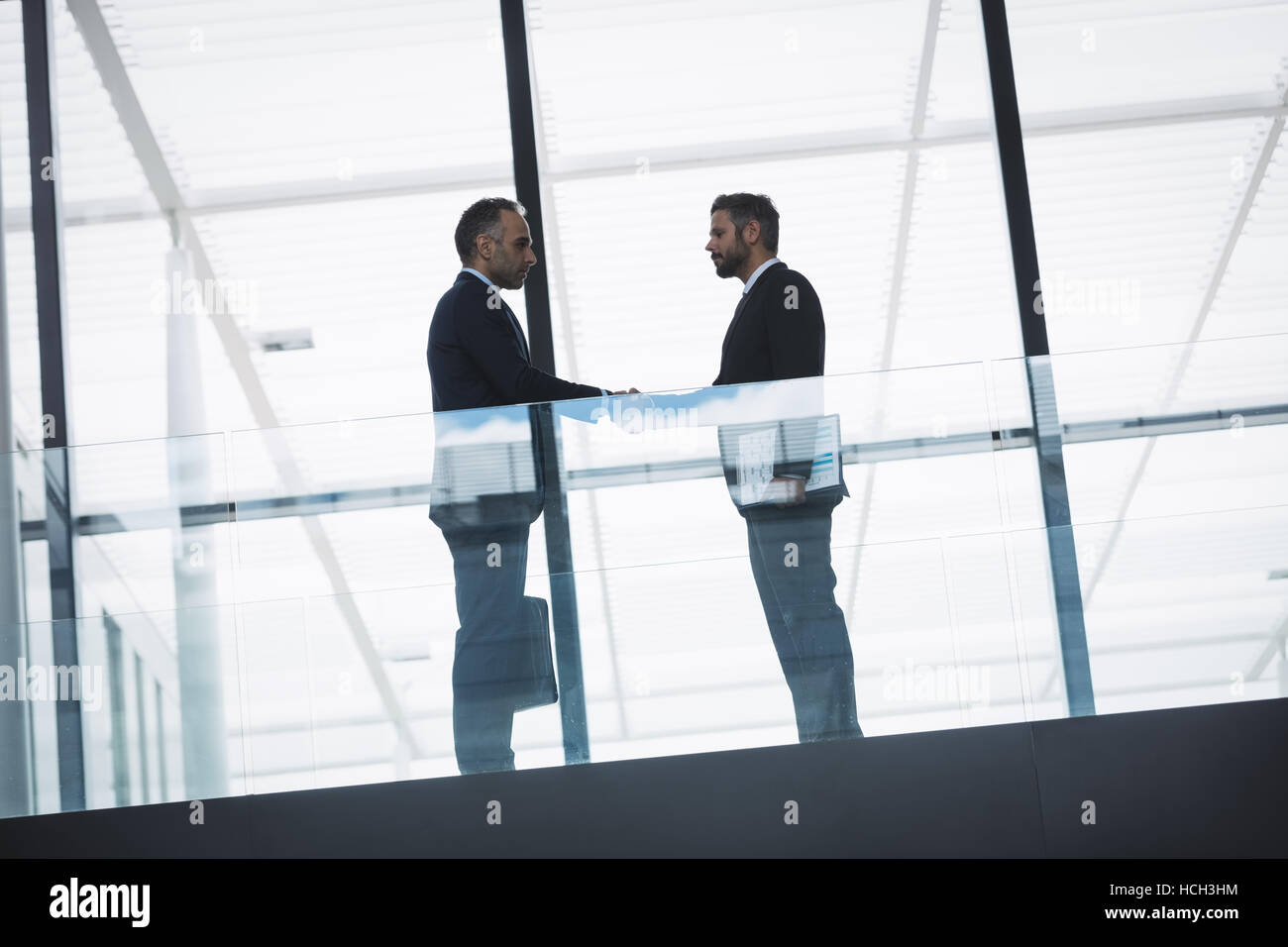 Businessman greeting a colleague inside office building Stock Photo - Alamy