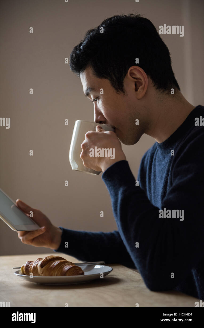 Man using digital tablet while having breakfast Stock Photo - Alamy