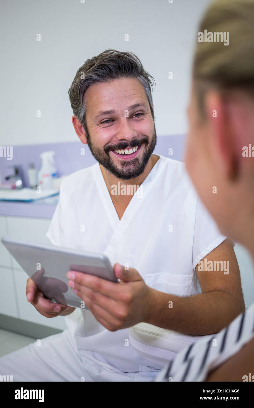 Doctor holding a digital tablet while talking with patient Stock Photo ...