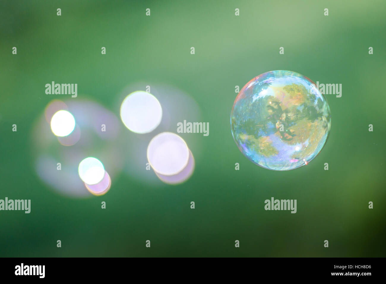 One bright soap bubble floating in focus with two de-focused bubbles ...