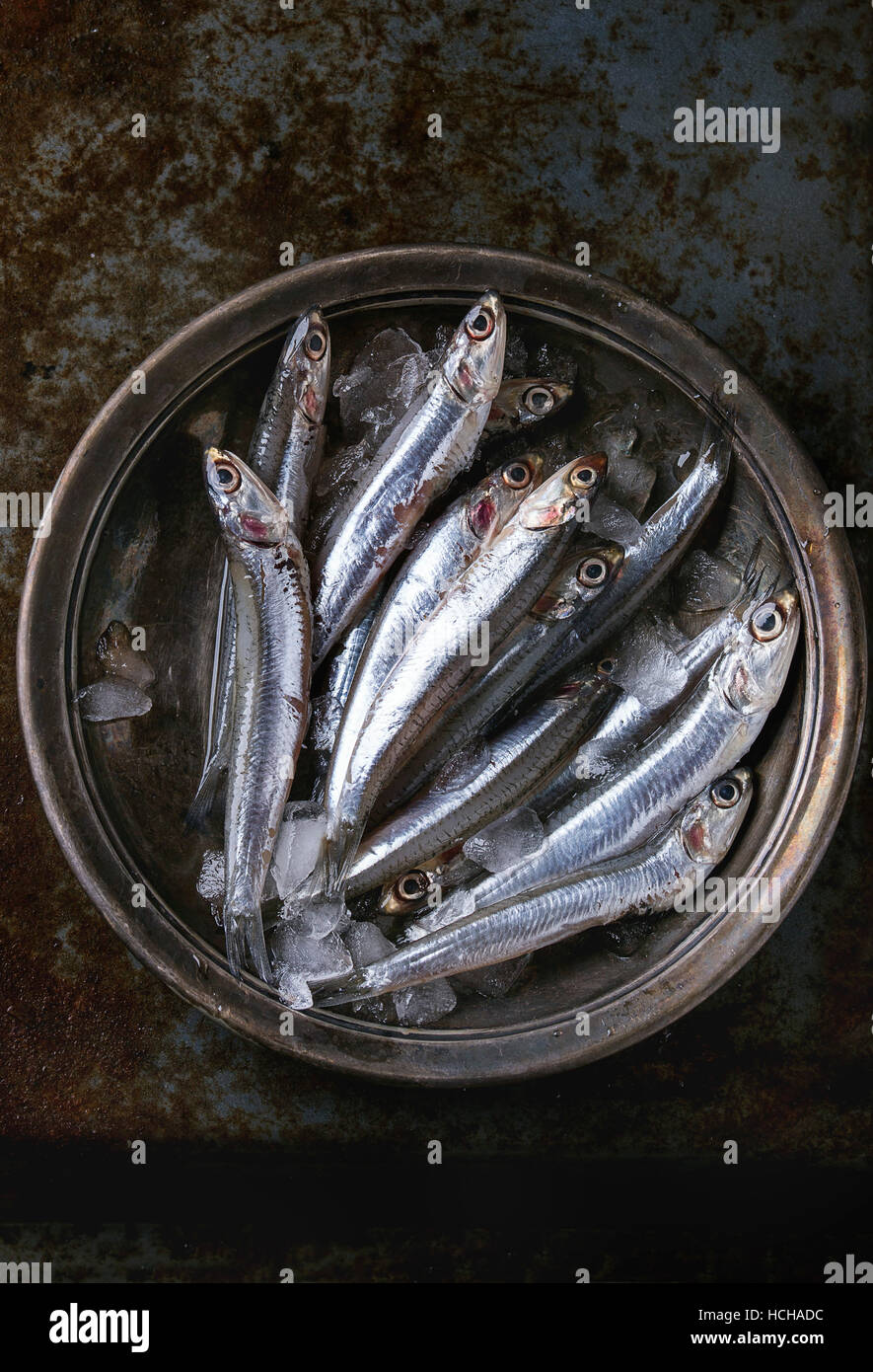 Lot of raw fresh anchovies fishes on crushed ice in vintage plate over ...