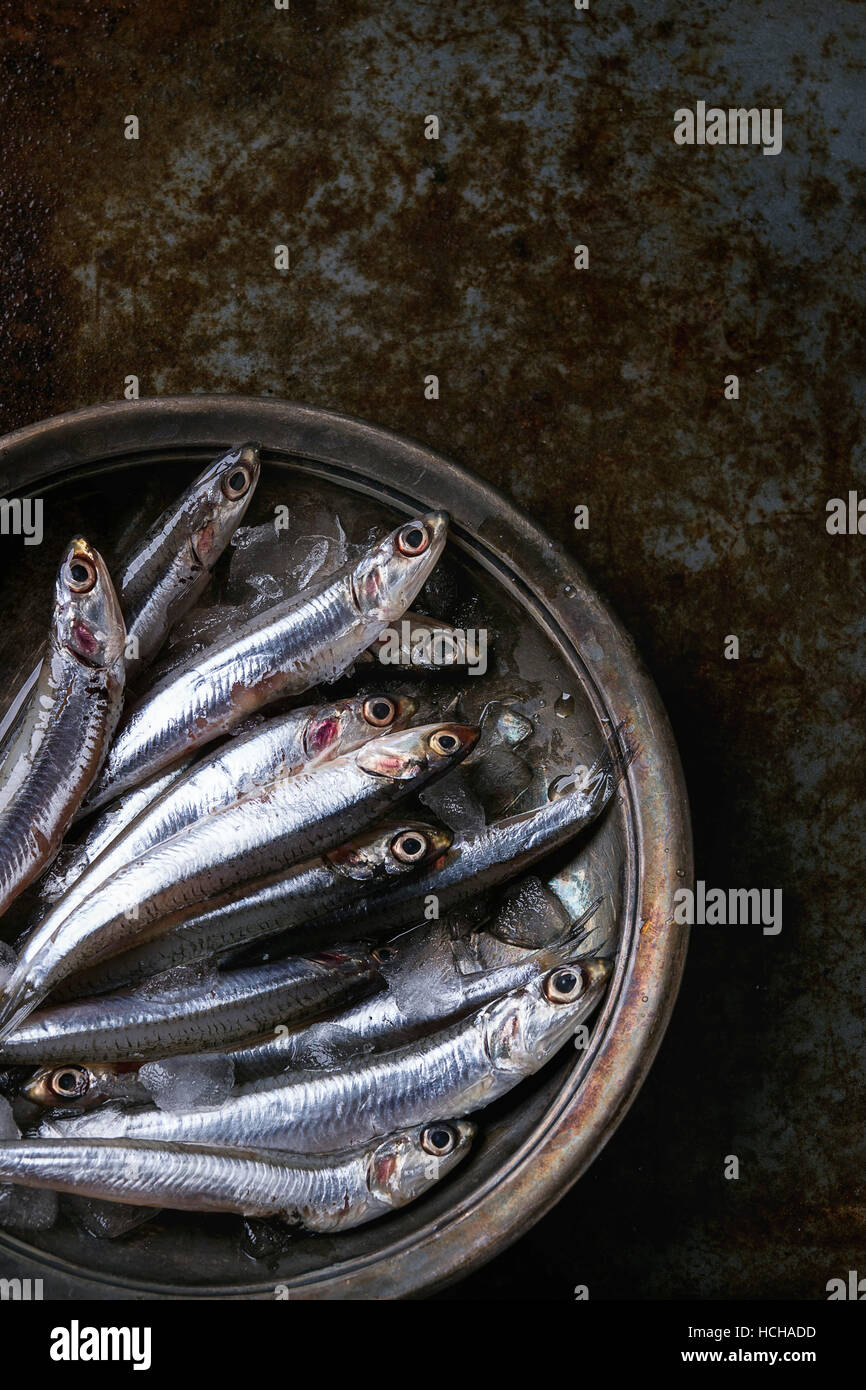 Lot of raw fresh anchovies fishes on crushed ice in vintage plate over ...