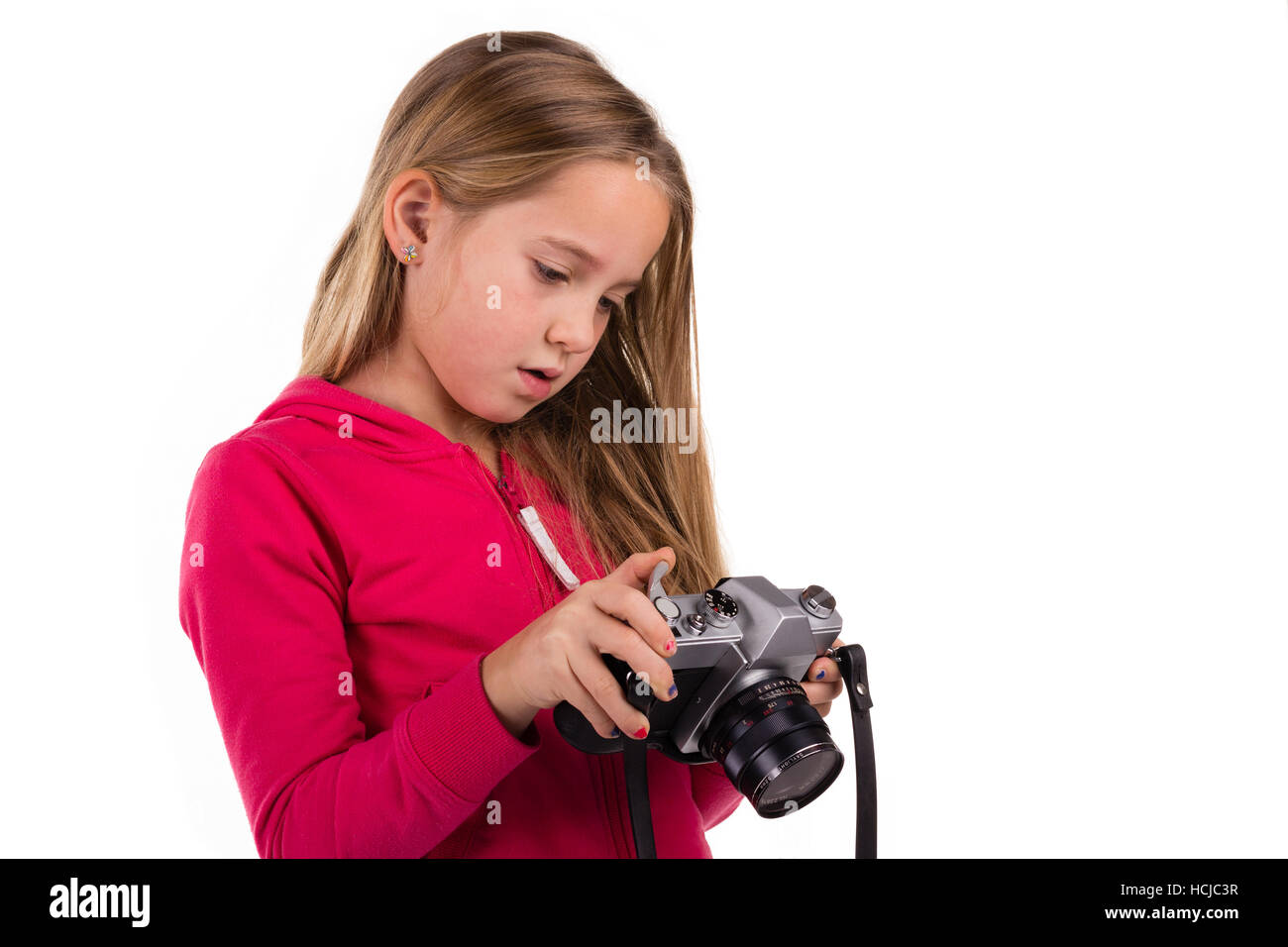 Young girl looking down on a vintage SLR camera isolated on a white ...