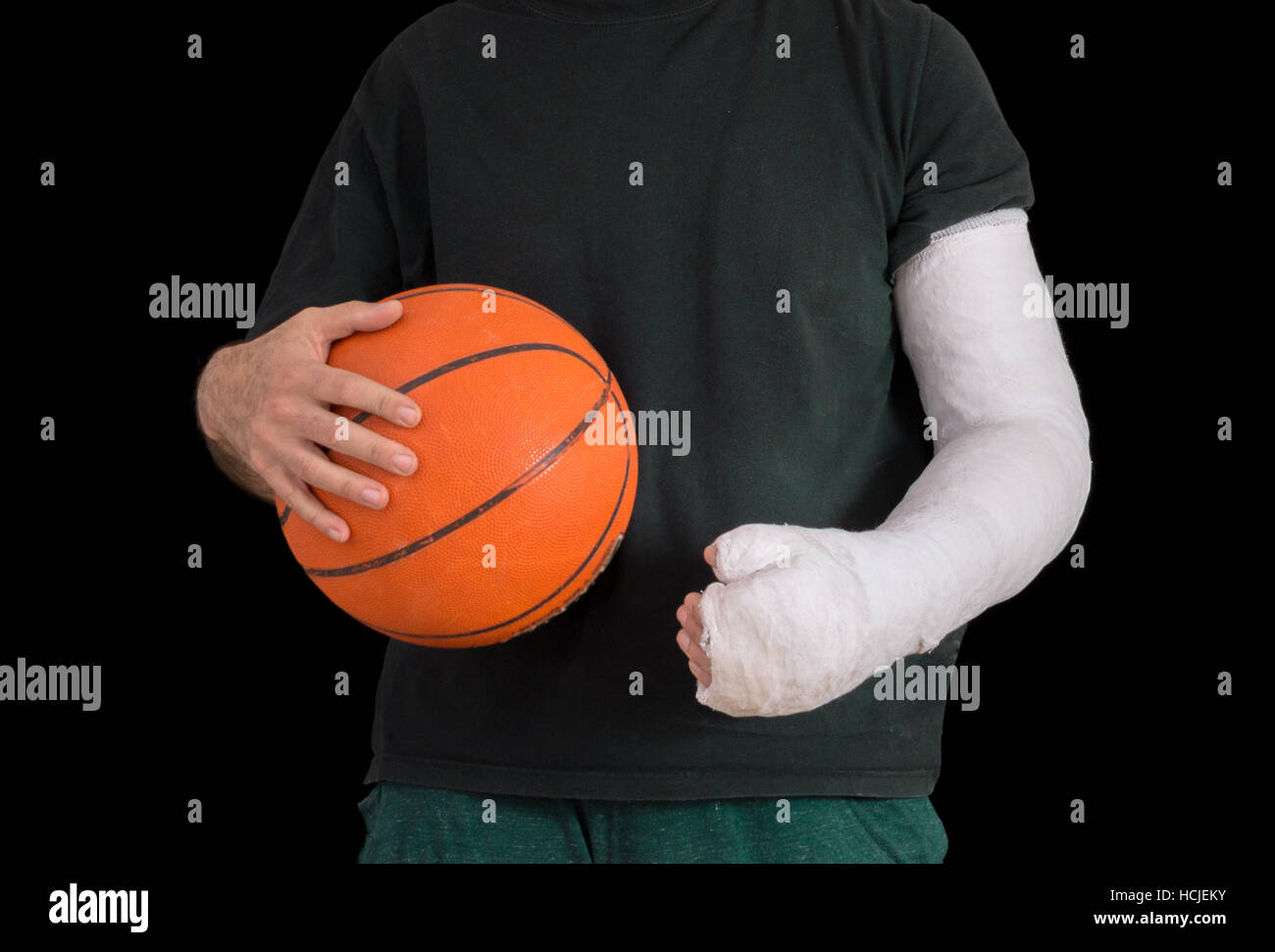 Young man sporting a bright white arm cast, holding a basketball after ...