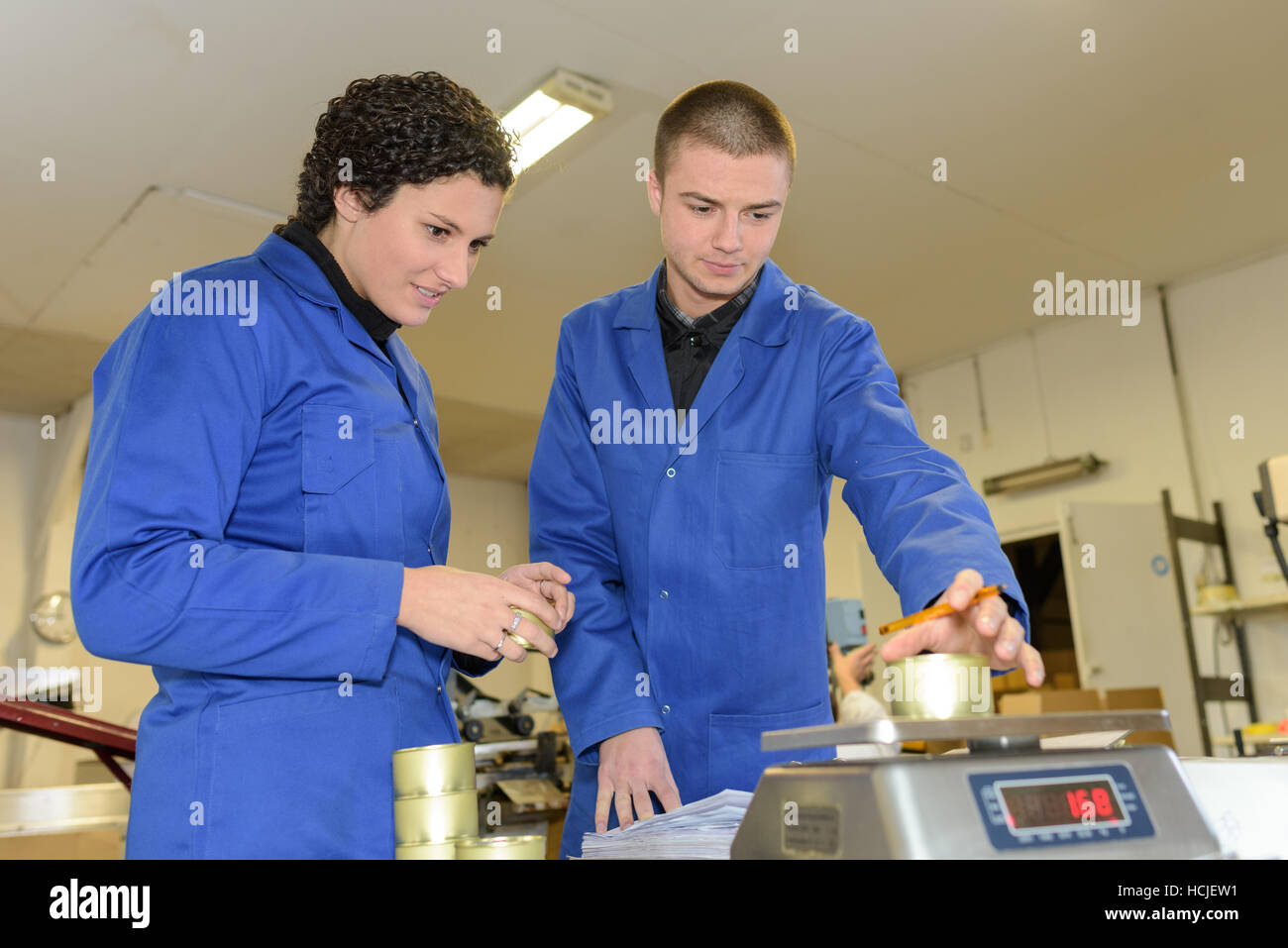Young workers weighing object Stock Photo - Alamy