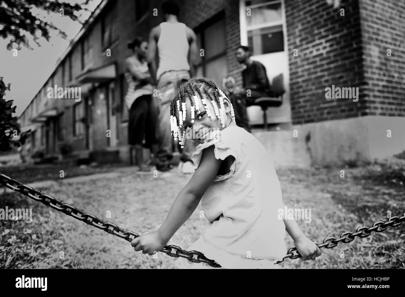 A little girl swings on the chain in the parking lot of government ...