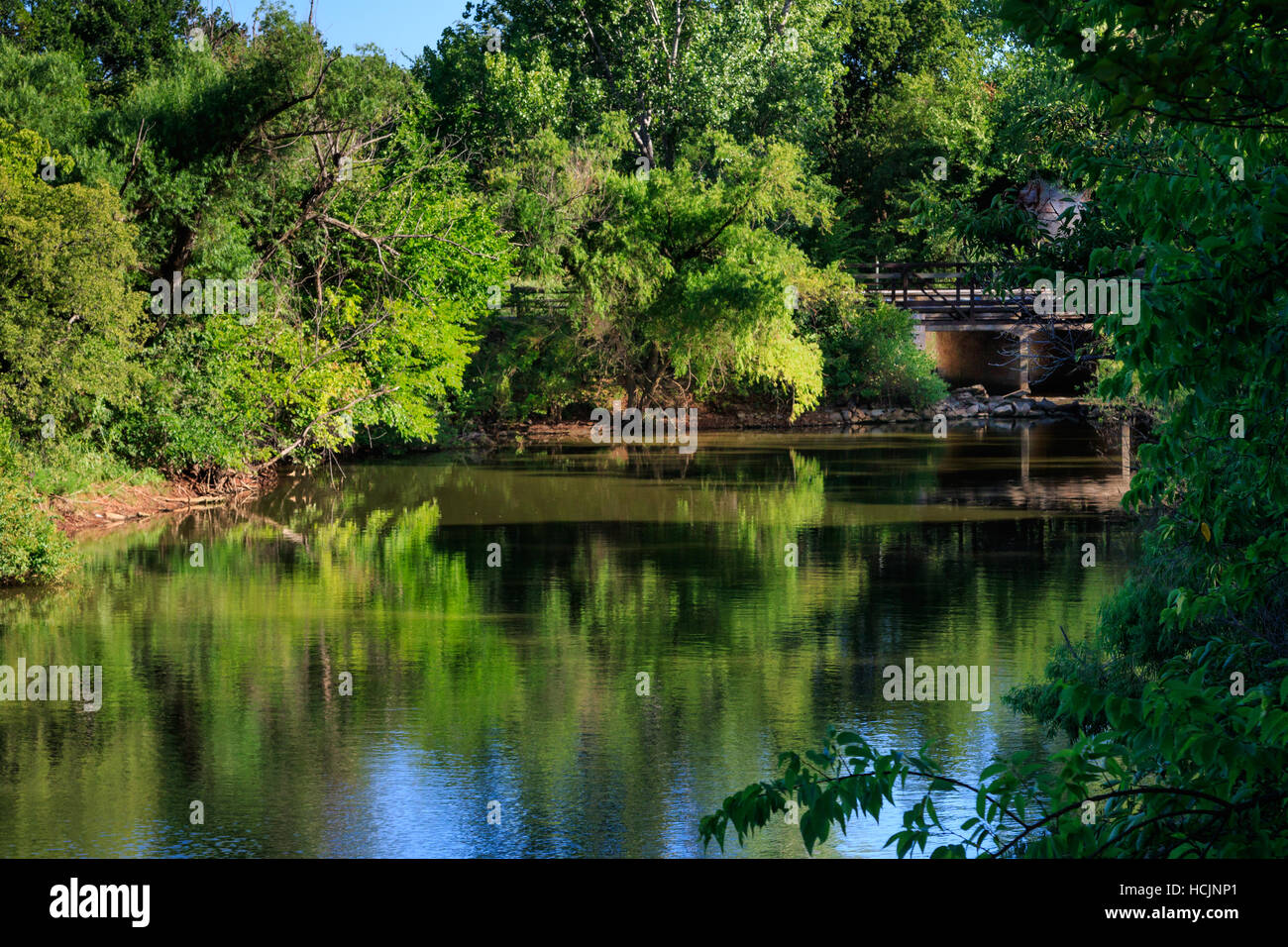 An old bridge covered in trees by a lake shore Stock Photo - Alamy