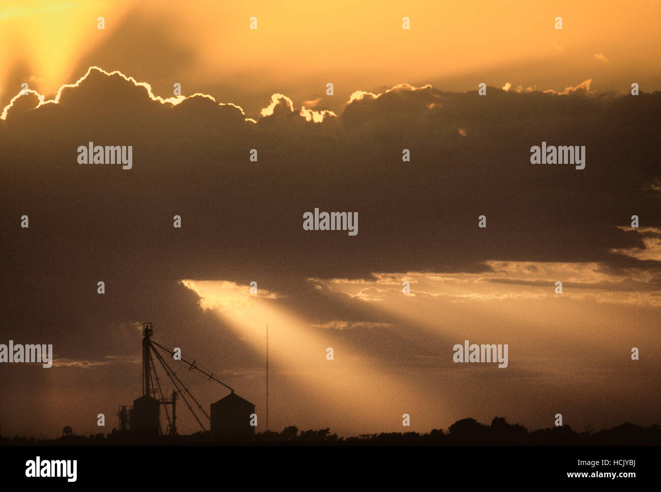 Sun is throwing shafts of light from this cloud over a silo on this ...
