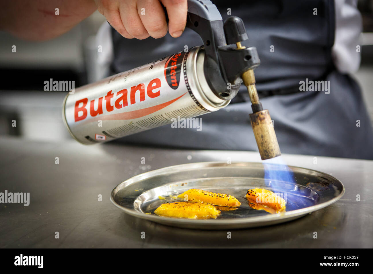 Chef with blowtorch and orange segments Stock Photo - Alamy