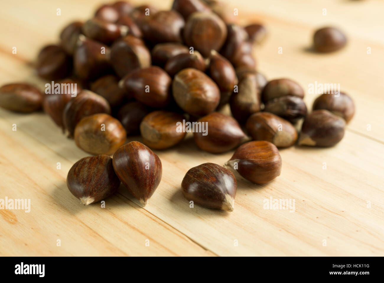 Chestnuts on pine wood background, illuminated with studio flax ...