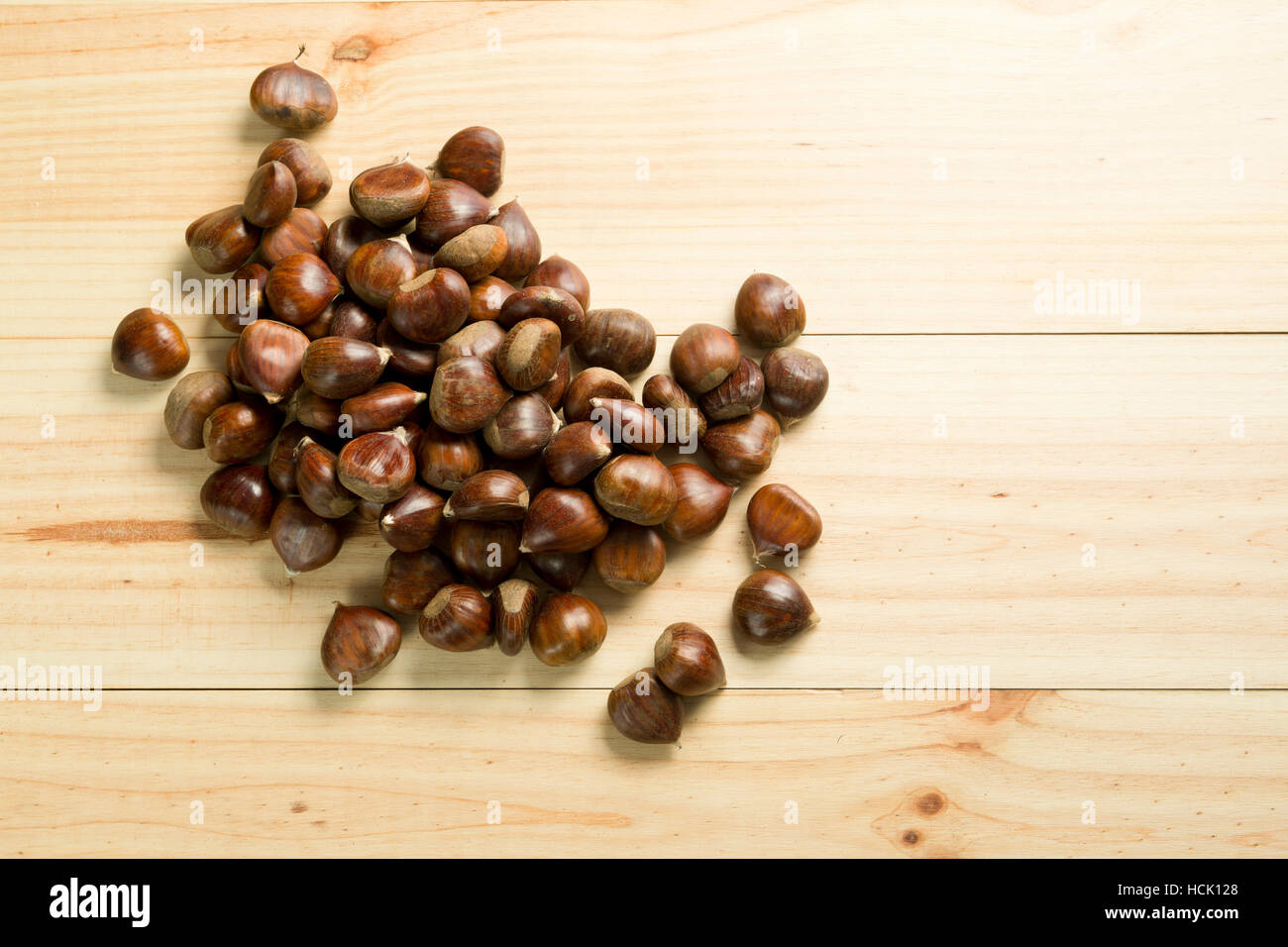 Chestnuts on pine wood background, illuminated with studio flax ...