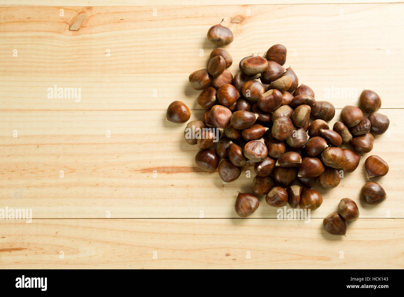Chestnuts on pine wood background, illuminated with studio flax ...