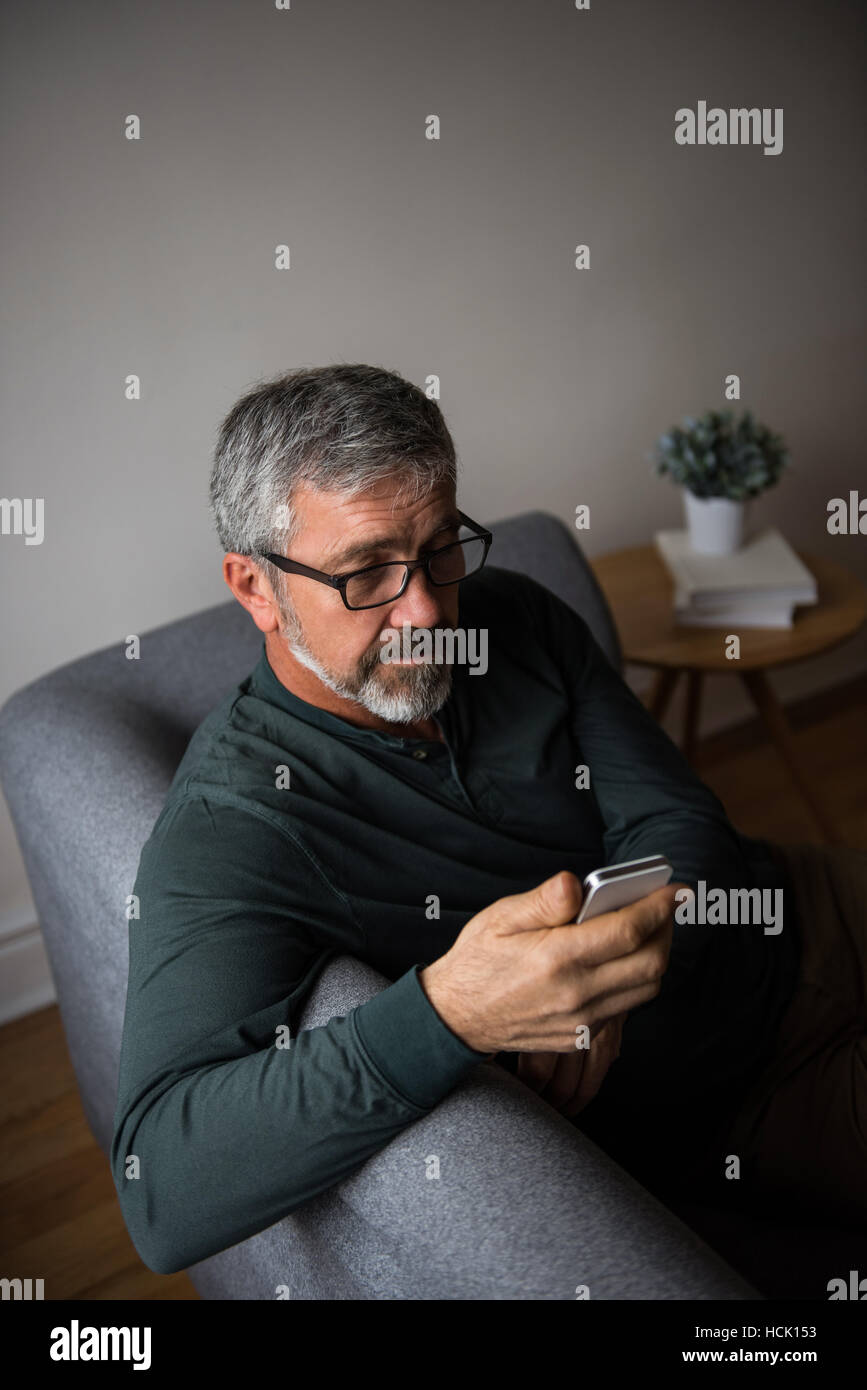 Man using mobile phone in living room Stock Photo - Alamy