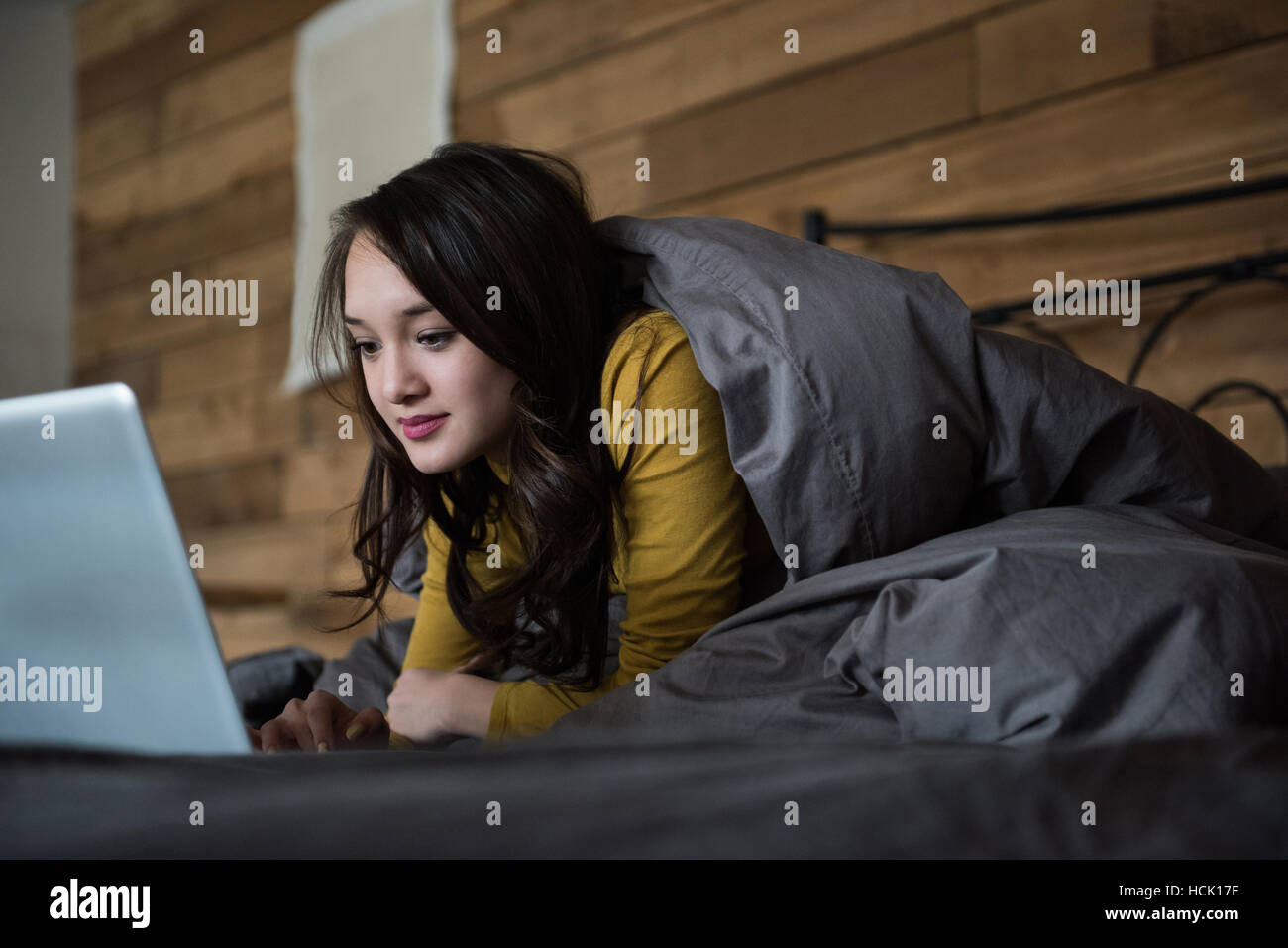 Woman lying on bed using laptop in bedroom Stock Photo - Alamy