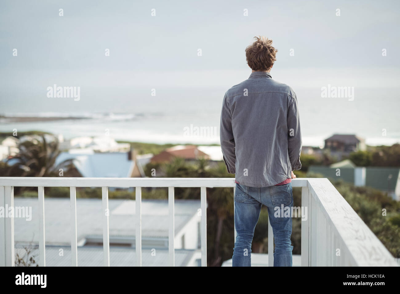 Rear view of man standing on balcony Stock Photo - Alamy