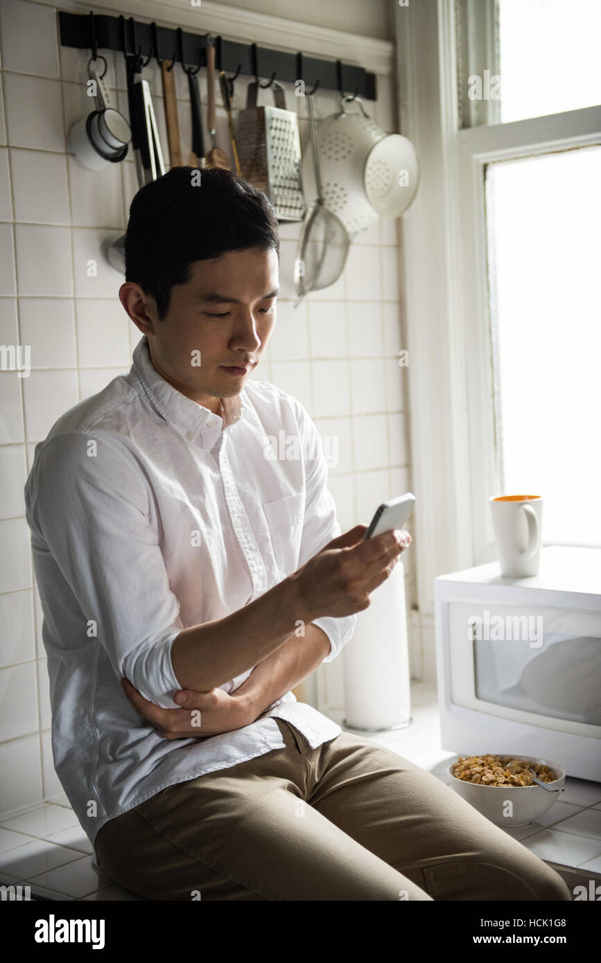 Man using mobile phone in kitchen Stock Photo - Alamy