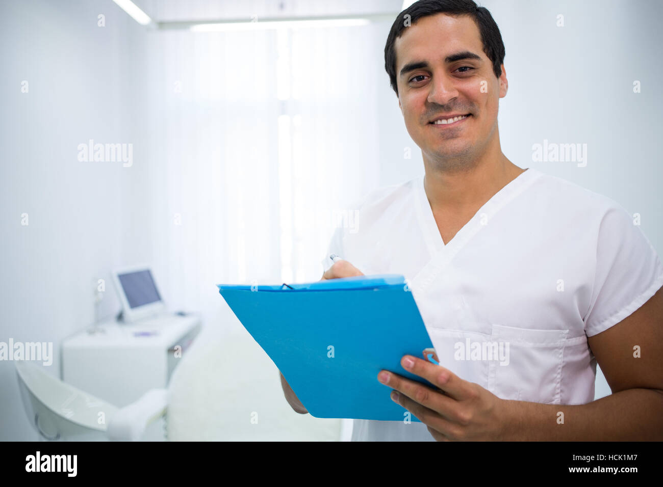 Smiling doctor holding a medical file at clinic Stock Photo - Alamy