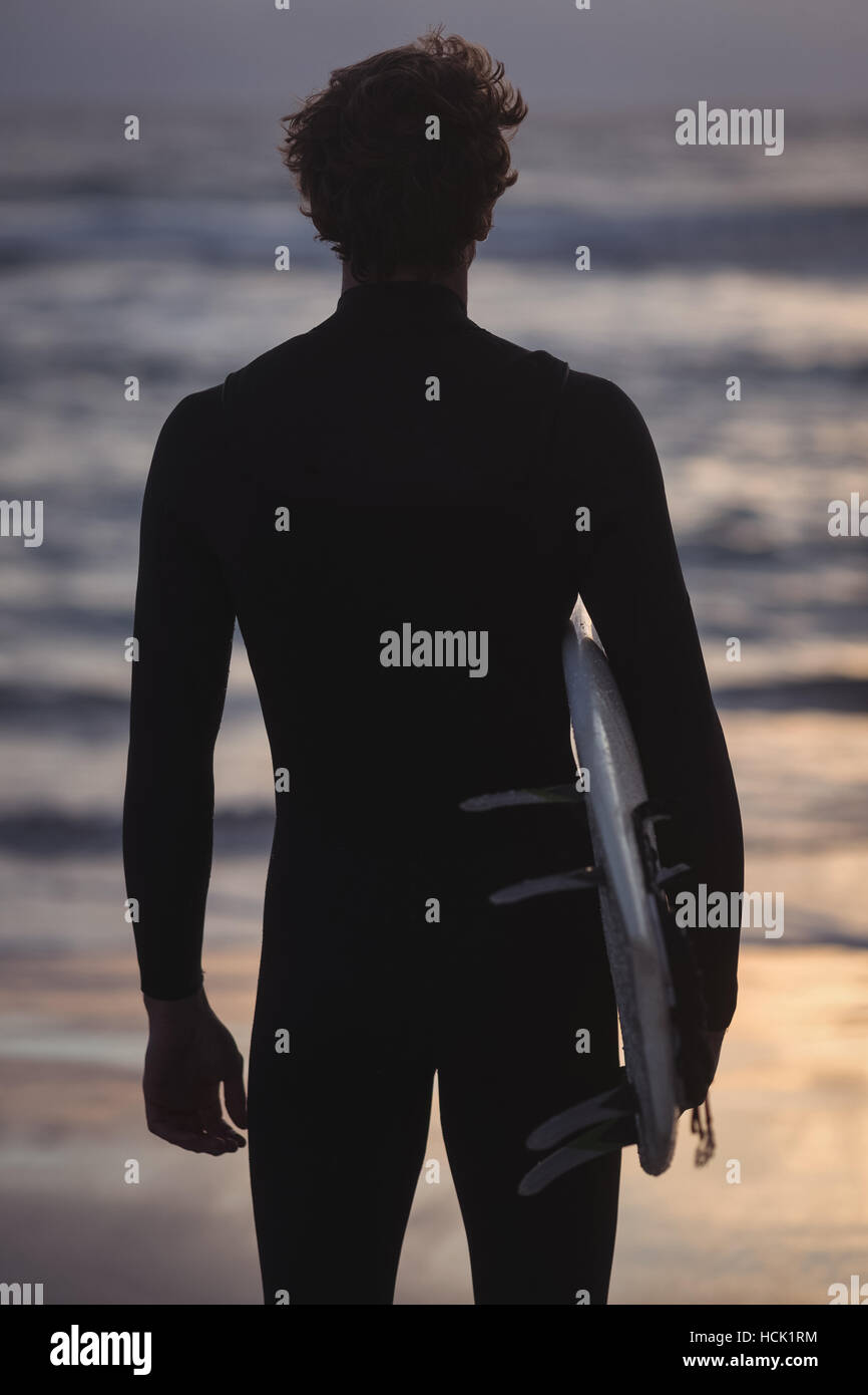 Man carrying surfboard standing on beach Stock Photo - Alamy