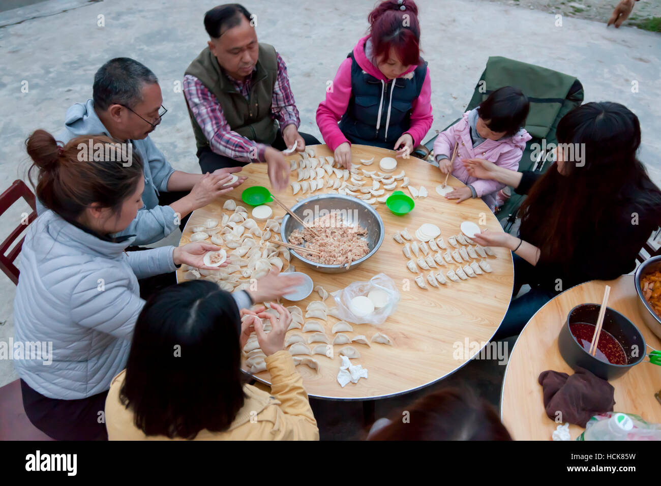 A group of friends make fresh dumplings for dinner during a farm-stay ...