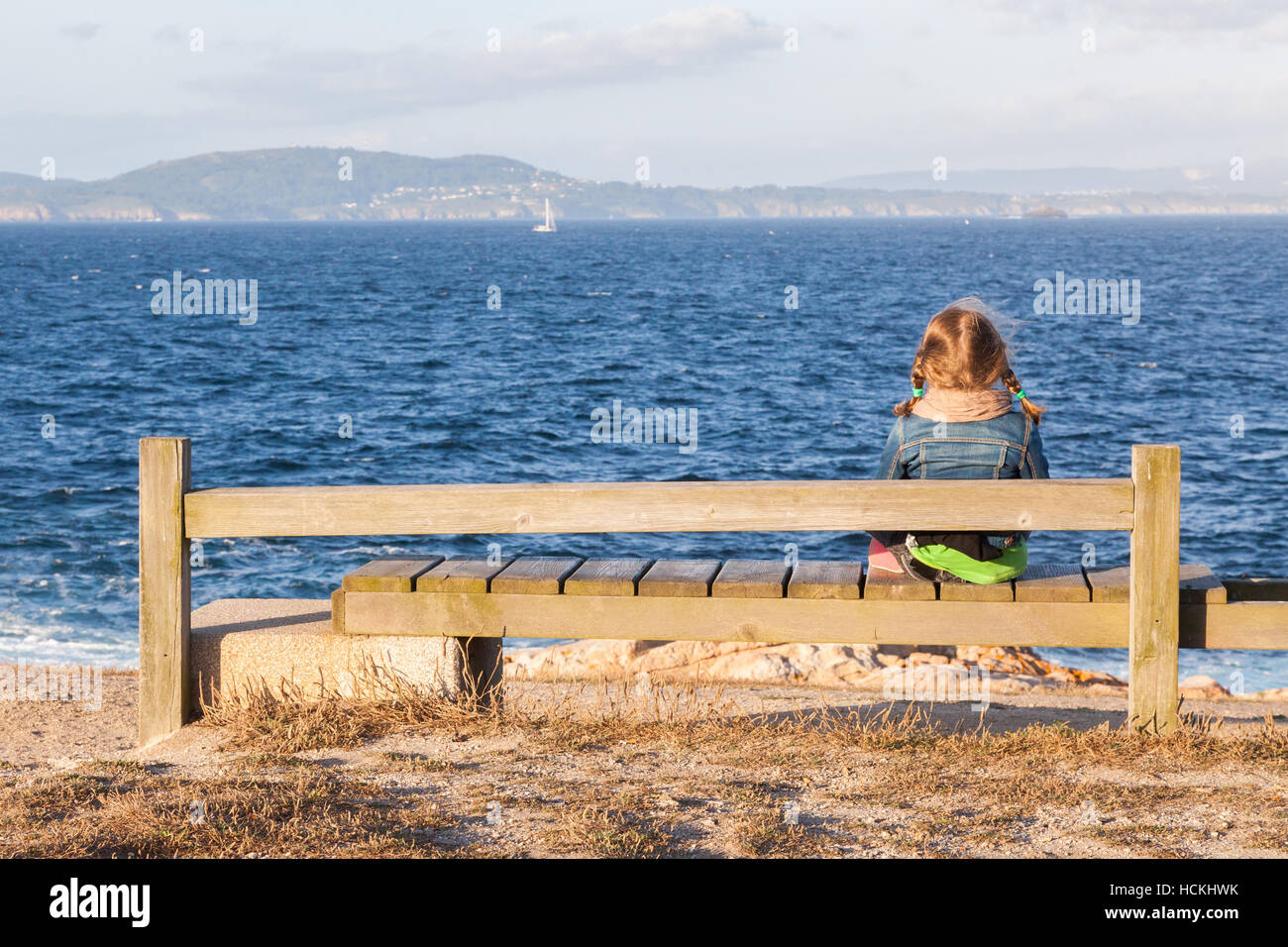 Girl sitting on a bench facing the sea Stock Photo - Alamy