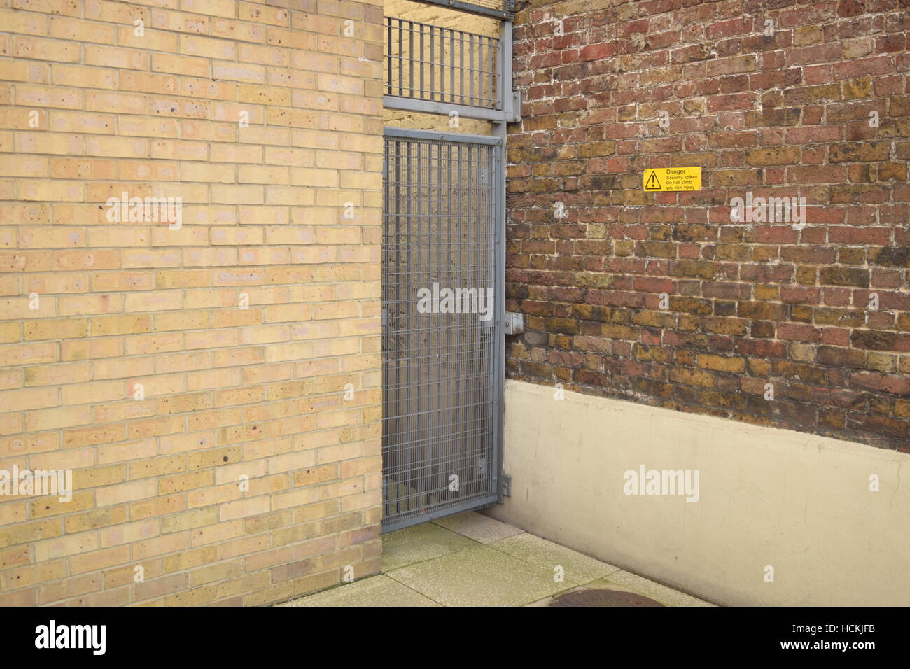 Metal security door in a brick wall with a yellow warning sign on the ...