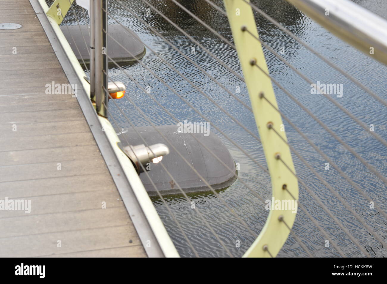 Side perspective of a modern metallic bridge railing with small orange ...