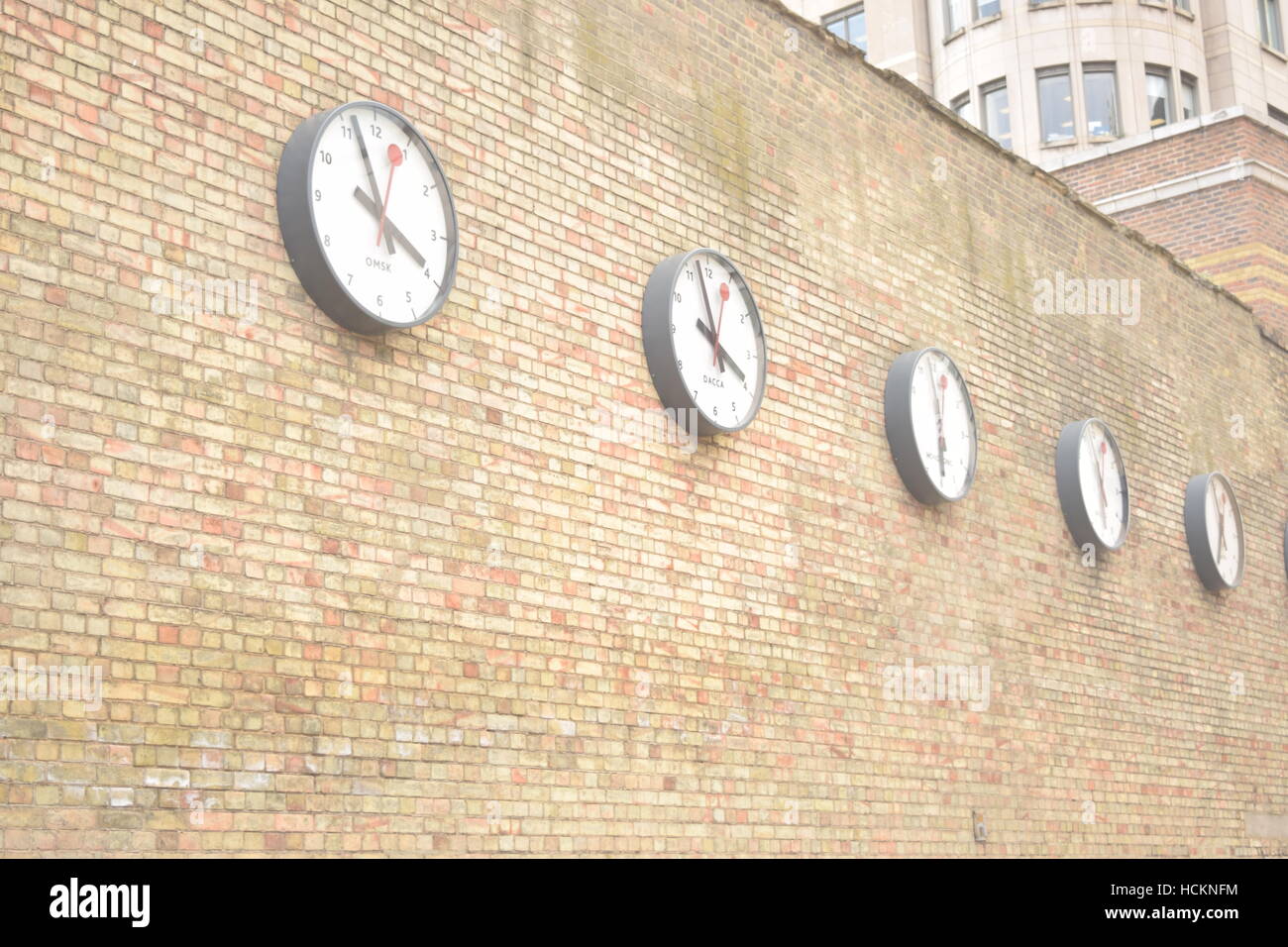 Five clocks on a brick wall showing international times Stock Photo - Alamy