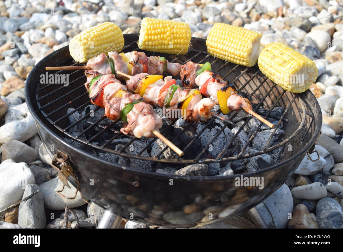 Mini barbecue on the beach with chicken and sweetcorn Stock Photo - Alamy