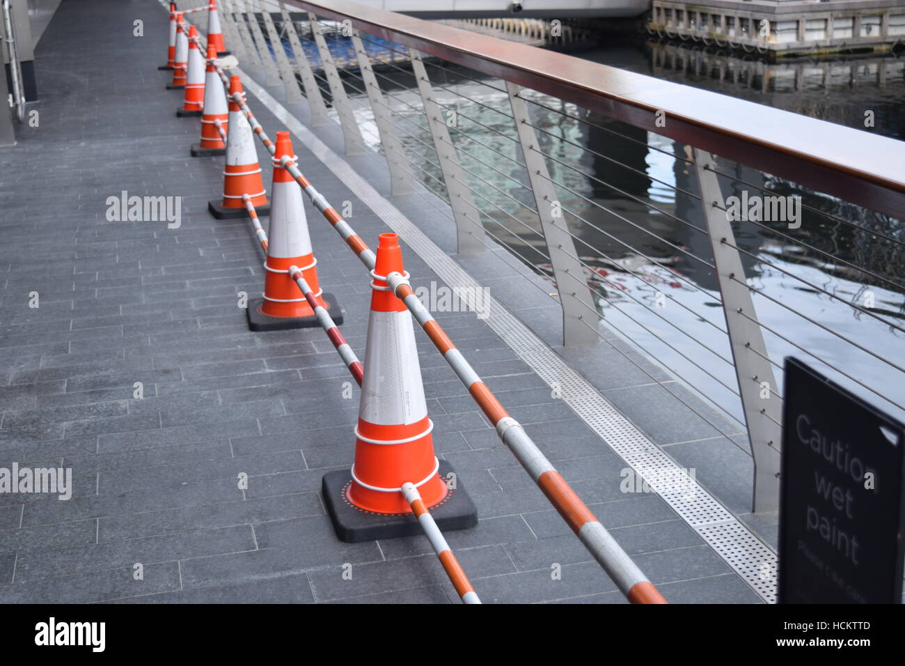Orange and white cones in a line on a bridge overlooking the river ...