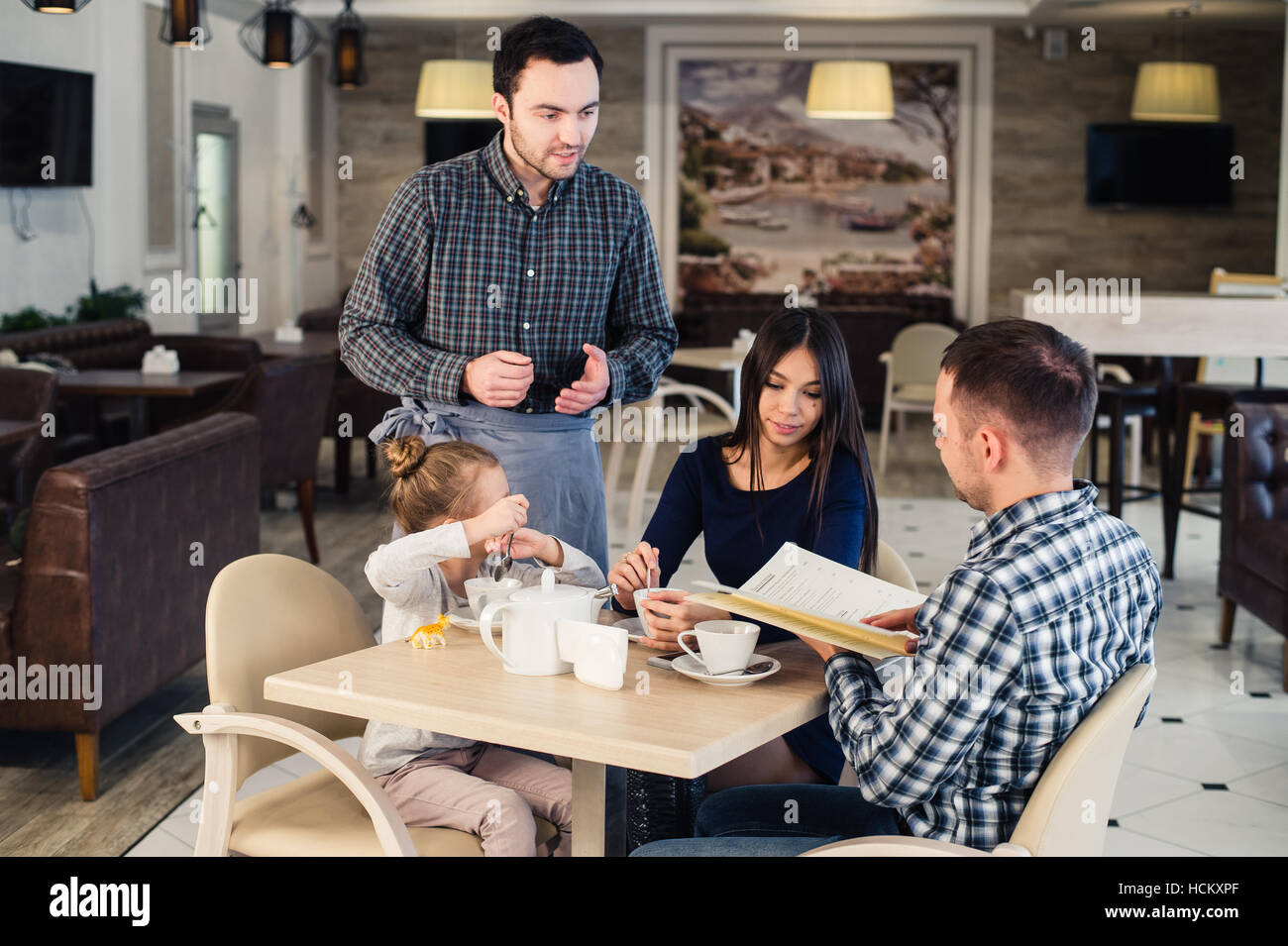 restaurant and holiday concept - waiter giving menu to happy family at ...