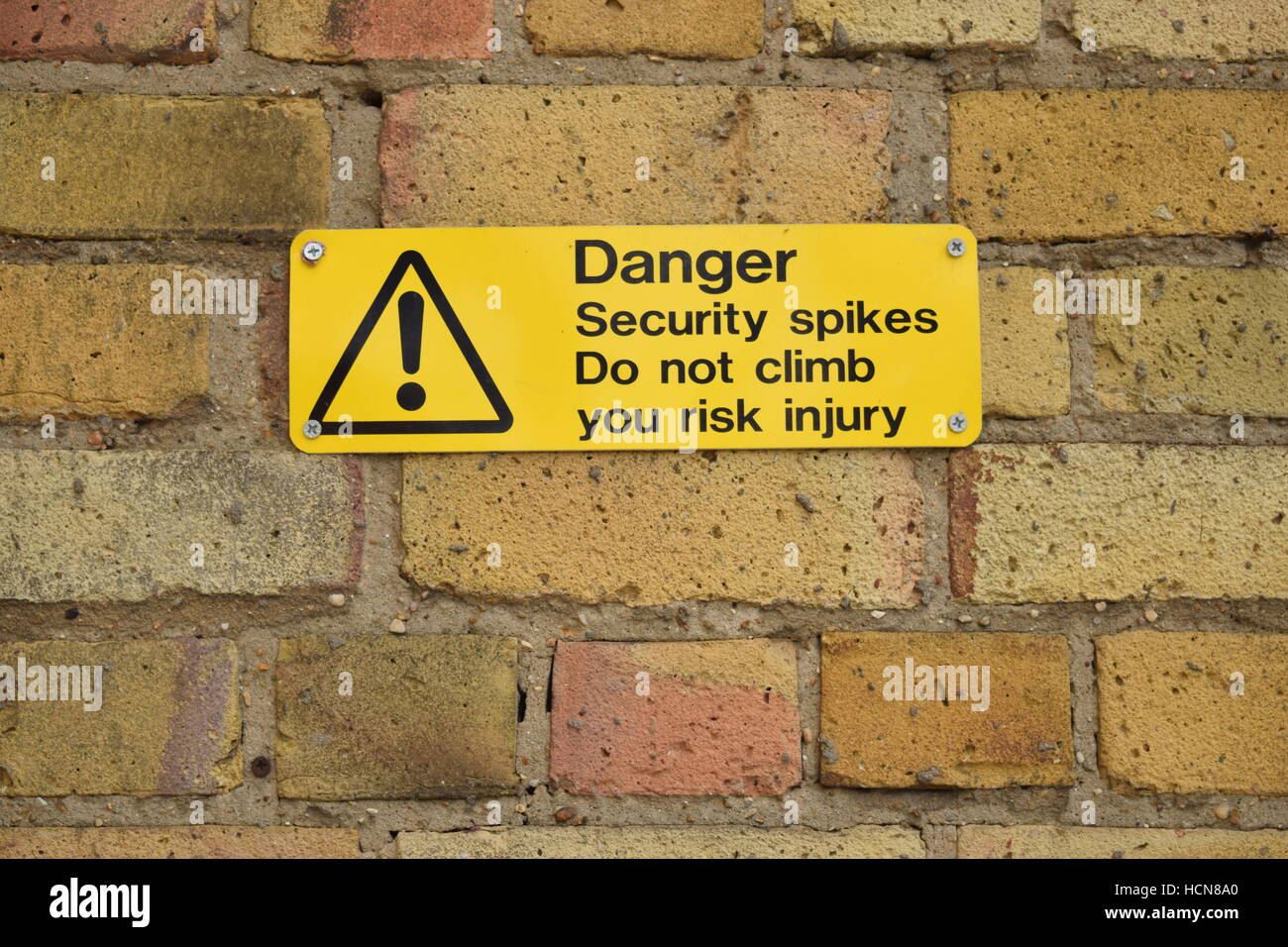 Yellow danger sign pinned on a yellow brick wall Stock Photo - Alamy