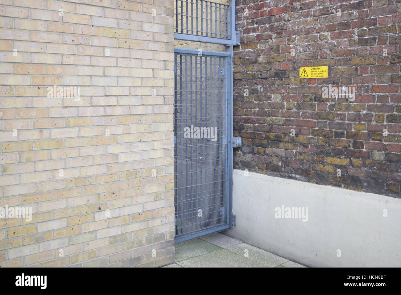 Small metallic side gate in between two brick walls Stock Photo - Alamy