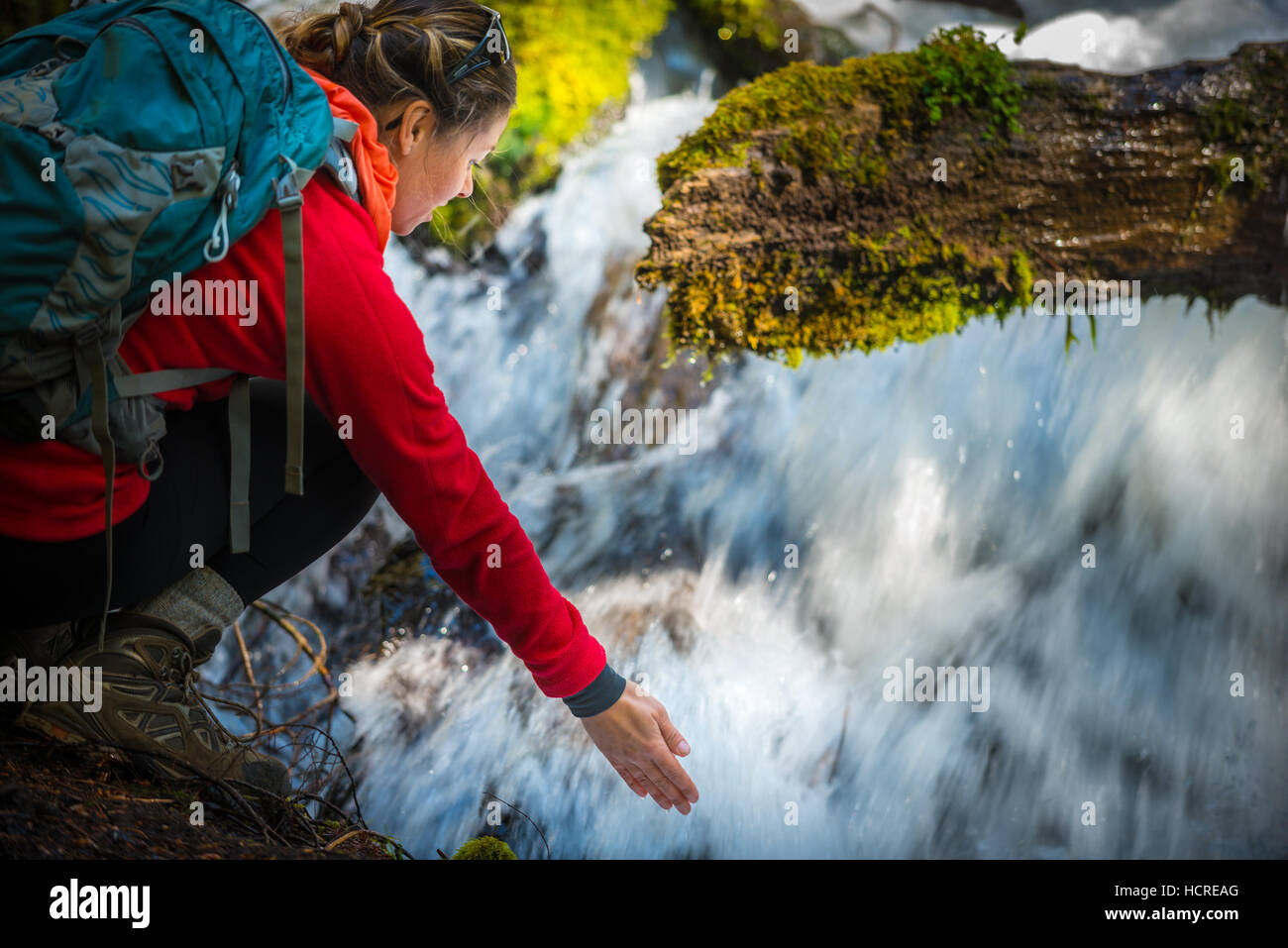 Oregon Tourist Backpacker holding hand under stream of running water of ...