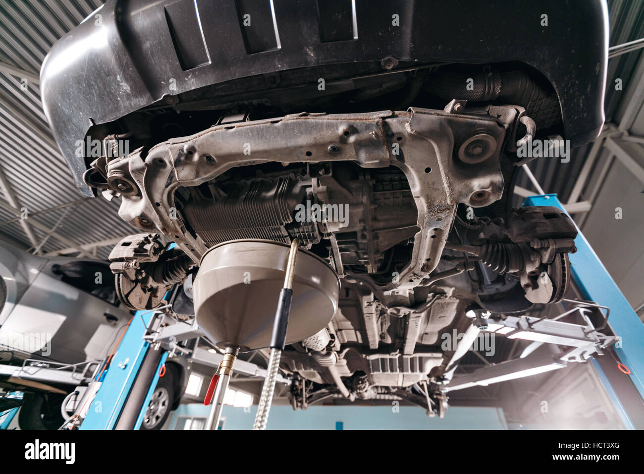 Change engine oil. working underneath a lifted car Stock Photo - Alamy