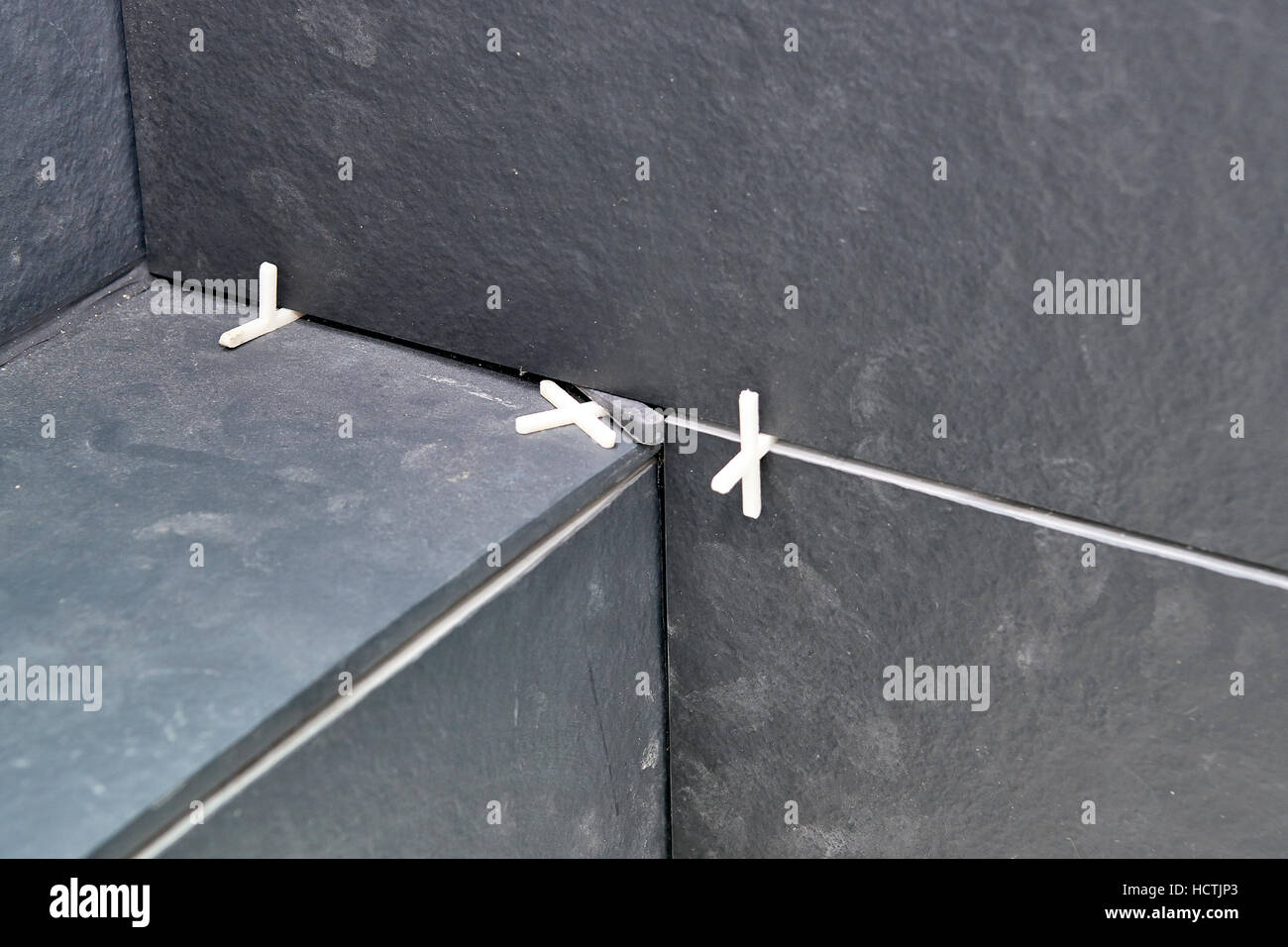 Installing the tiles with plastic crosses on the wall Stock Photo - Alamy