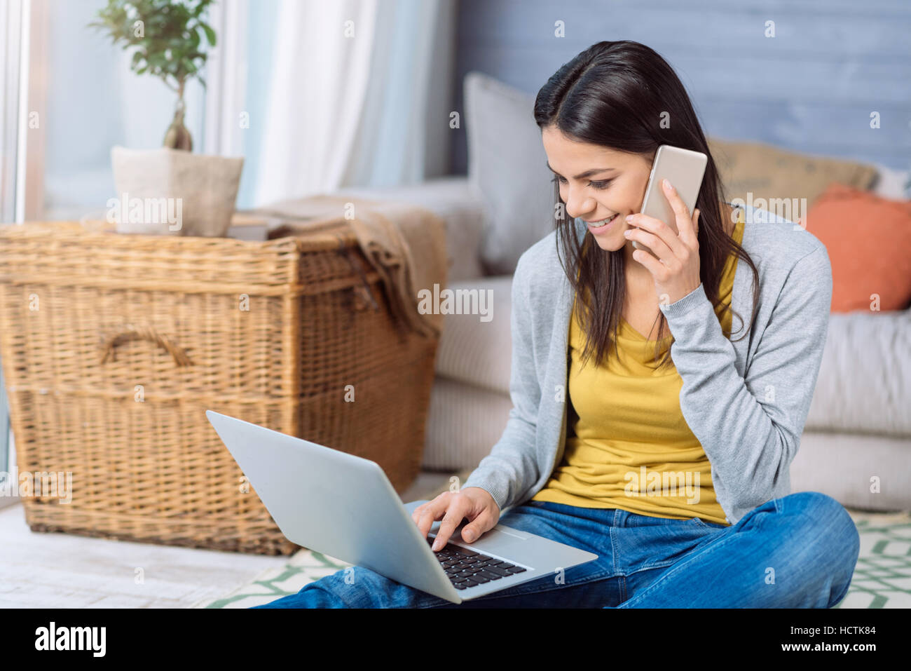 Cheerful woman using the laptop and speaking over the phone Stock Photo ...