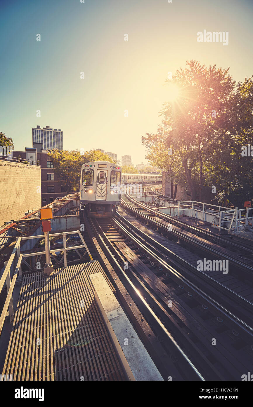 Vintage stylized train entering platform against rising sun in Chicago ...