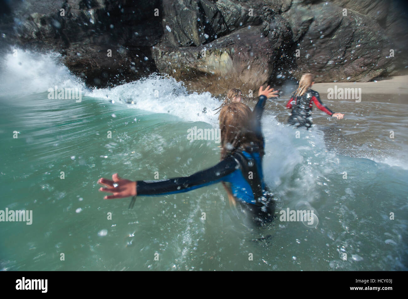 Girls jump in the waves at Kynance Cove, Cornwall, UK Stock Photo - Alamy