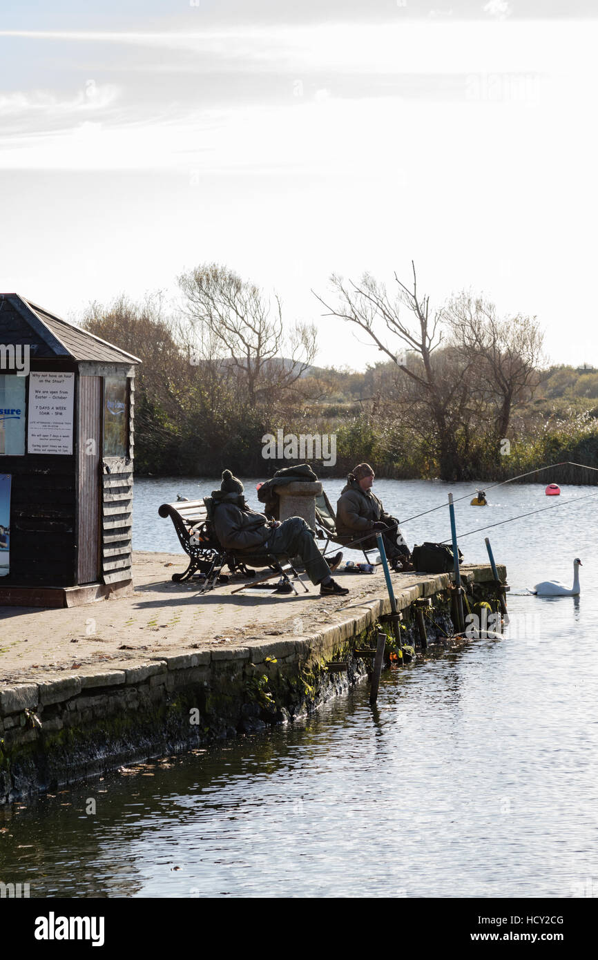 Anglers wrapped up against the cold fish off a pier in the River Stour ...