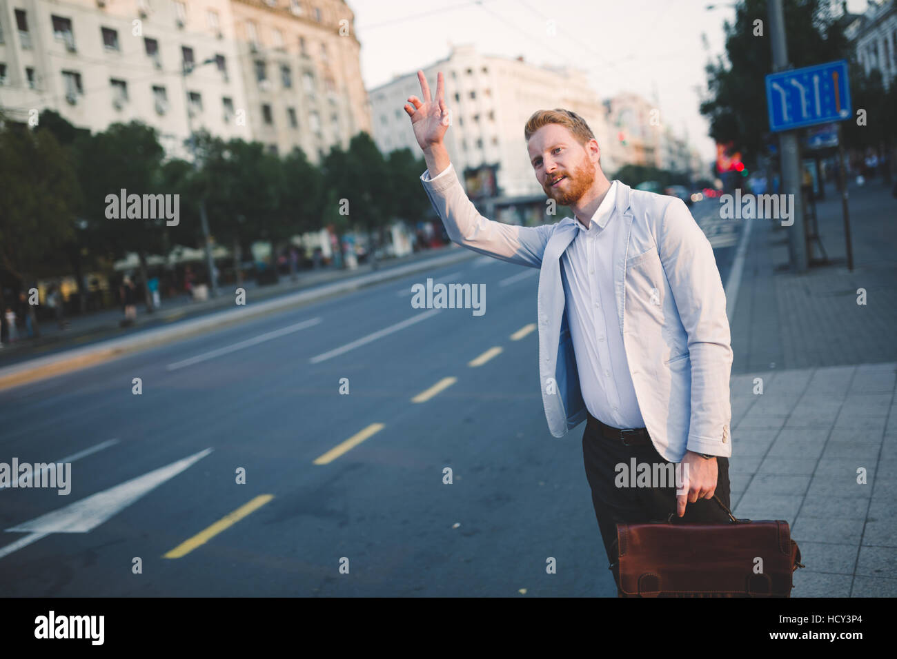 Handsome business hailing cab in city Stock Photo - Alamy