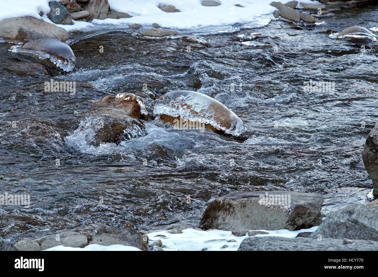Winter valley of frozen mountain river stream covered with ice and snow ...