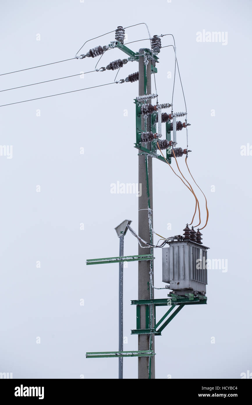 Electric transformer station and wires in winter covered snow and ice ...