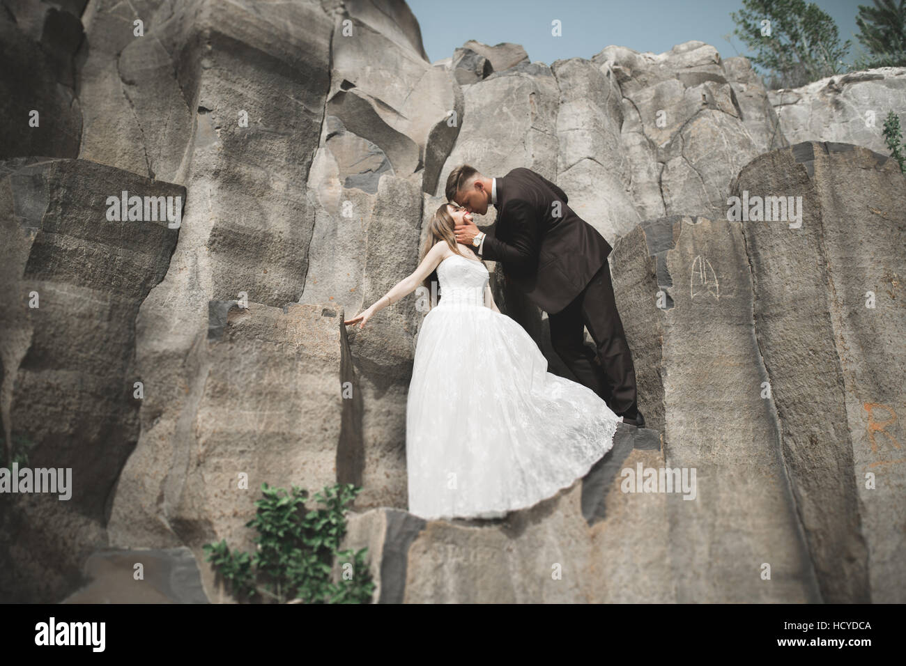 Wedding couple in love kissing and hugging near rocks on beautiful ...