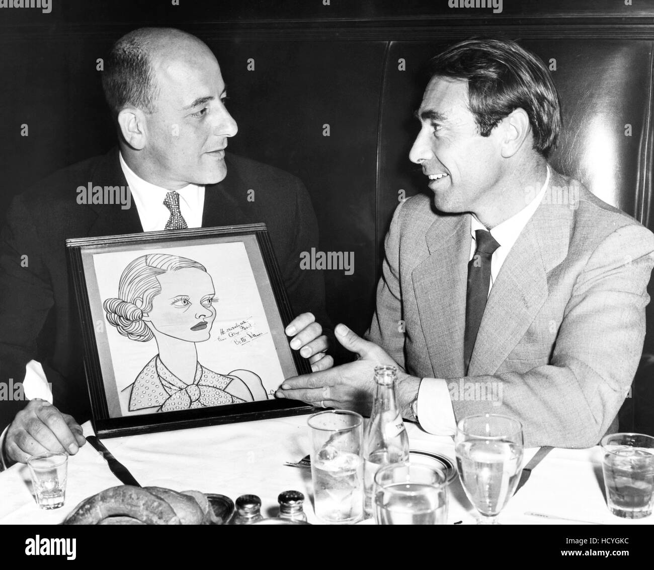 Gary Merrill, right, admires a caricature of his wife Bette Davis, held ...