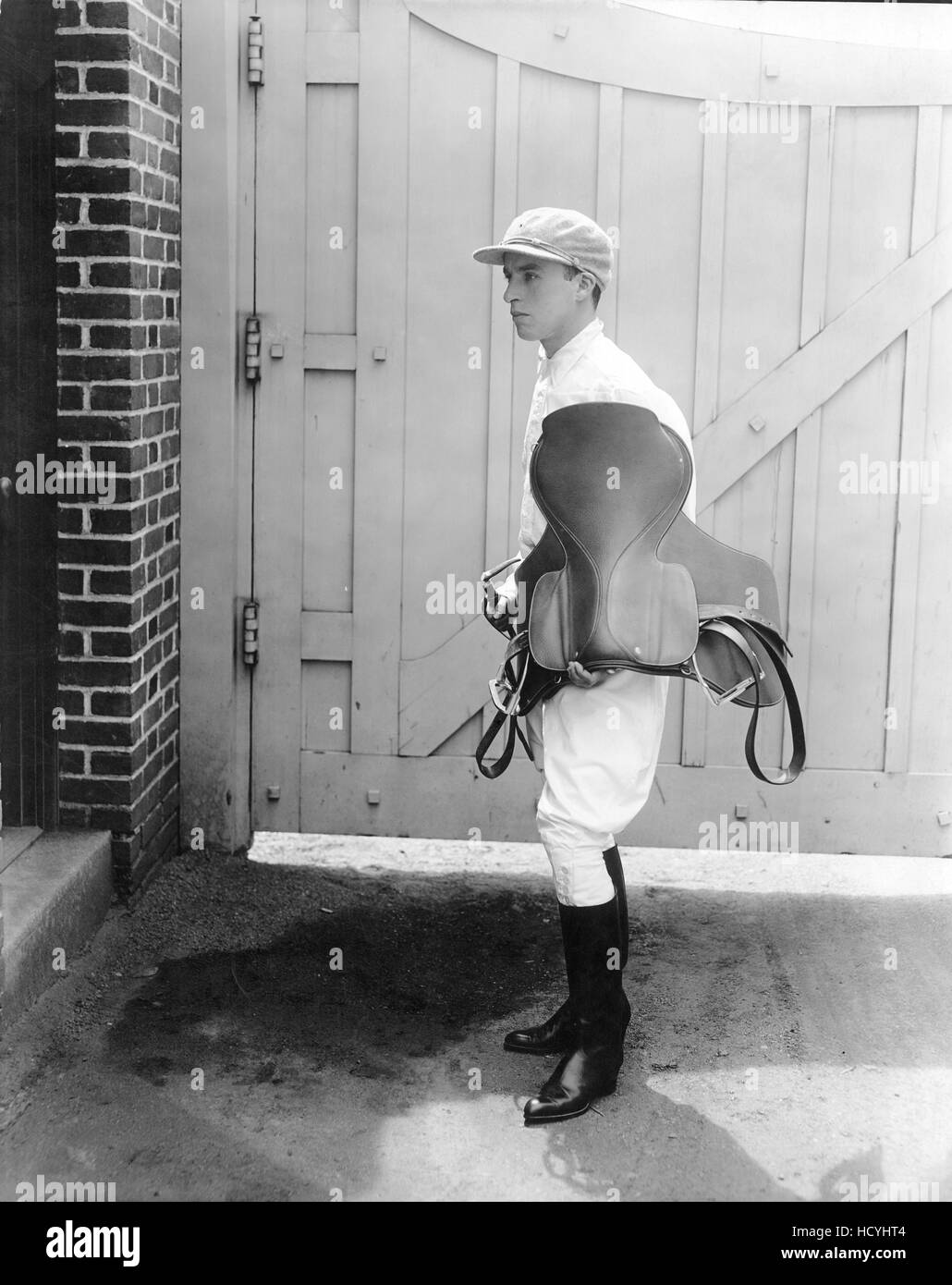 Charlie Chaplin, in horse riding outfit, holding a saddle, April, 1923 ...