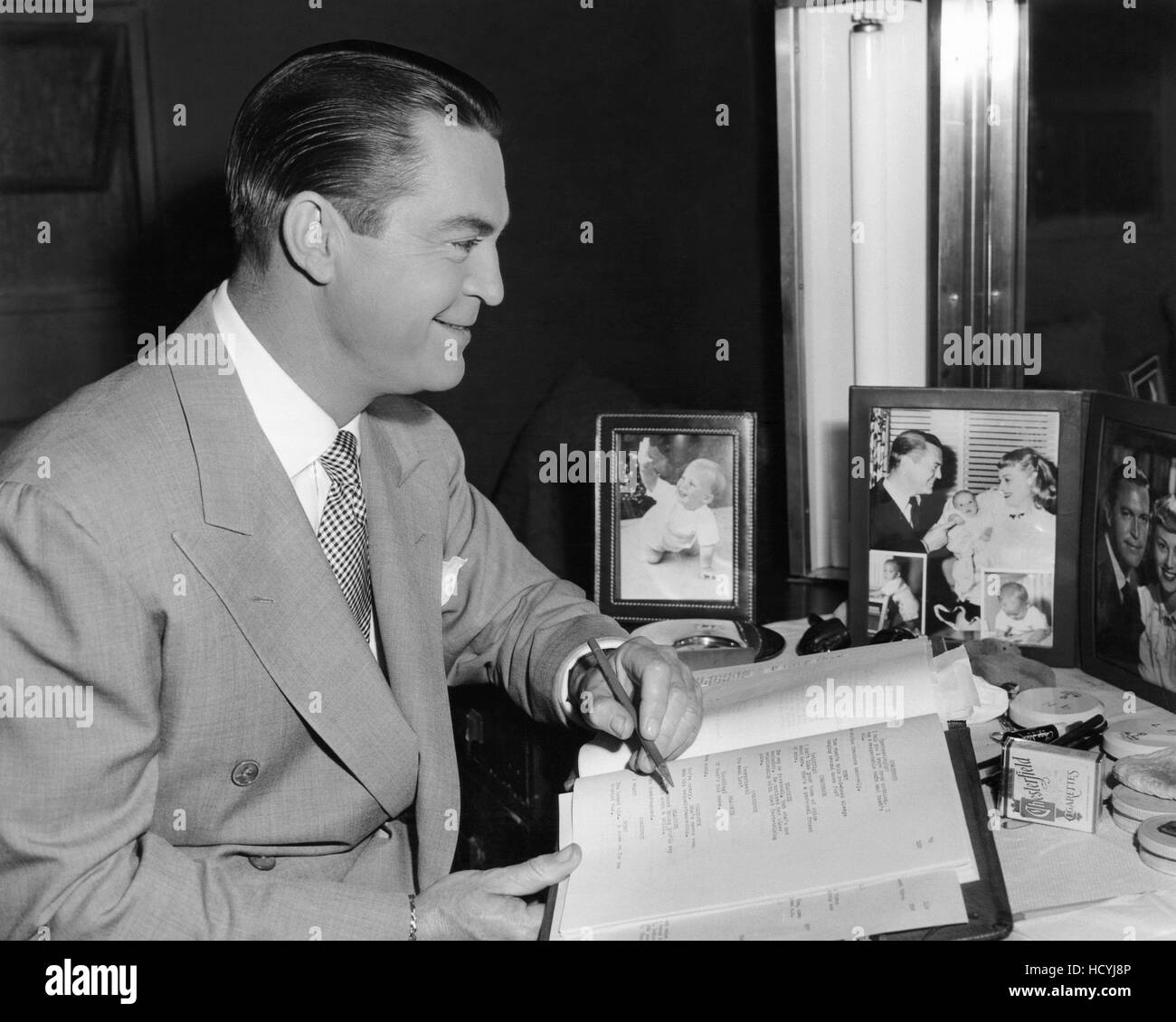Chester Morris glancing up from his script to look at a photo of his ...