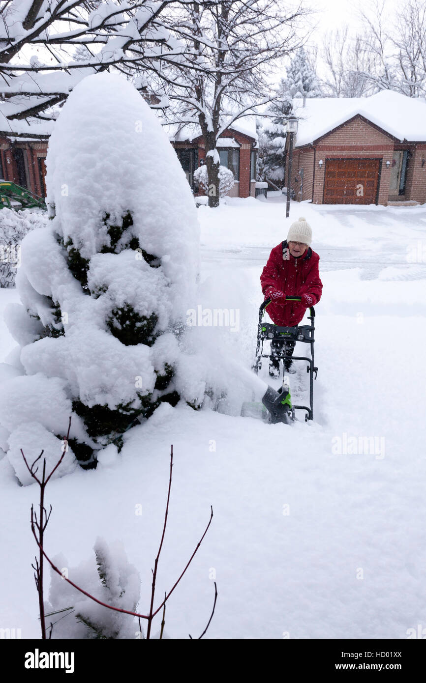 Woman Using Eco Friendly Snow Plow Is Plowing Her Driveway In The Winter With Lots Of New Snow