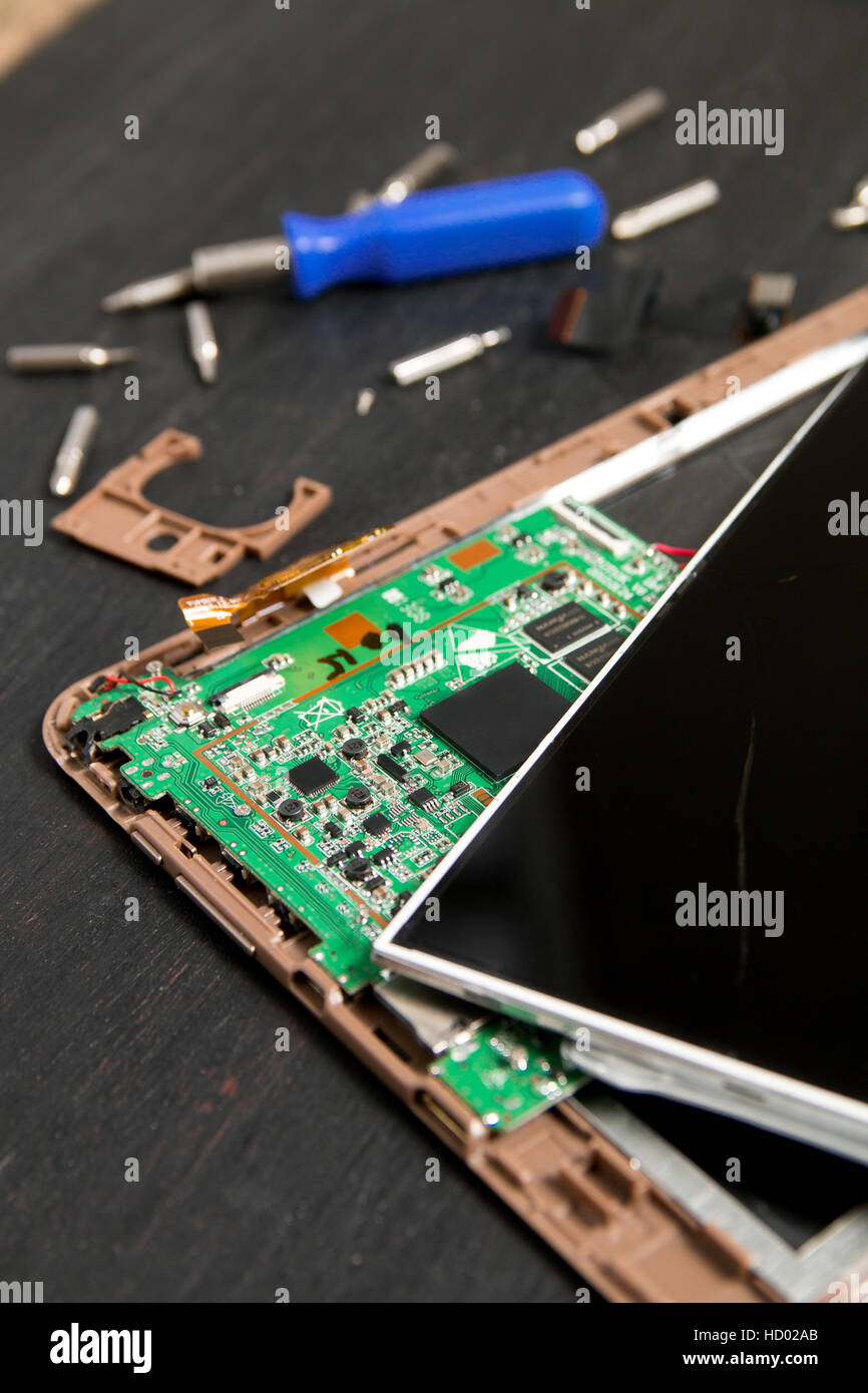 Process of PC Tablet device repair near screwdriver and bit on black ...