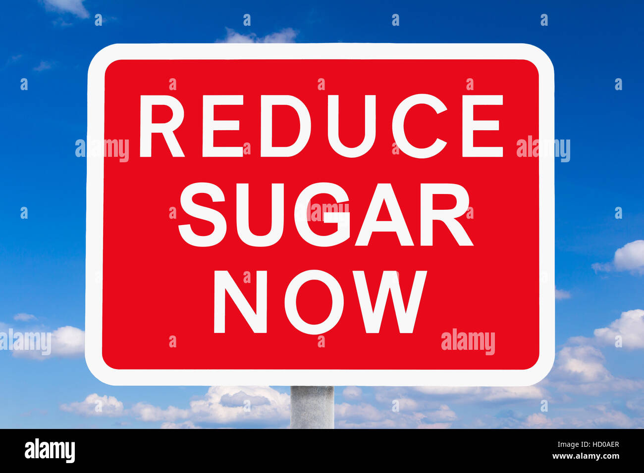 Red and white signpost REDUCE SUGAR NOW in front of a blue sky, symbol ...