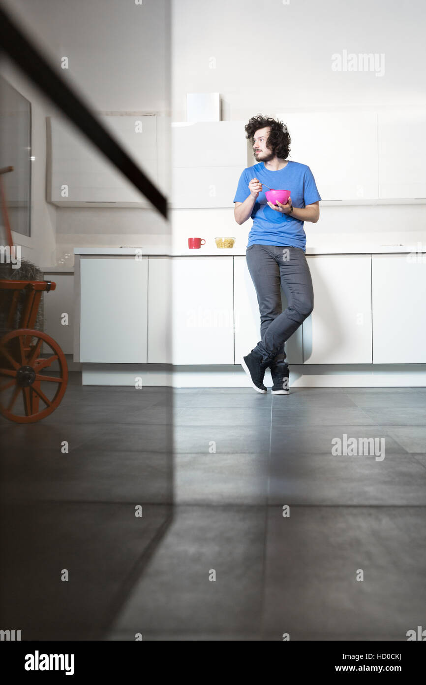 Young cheerful man eating cereal from a bowl in modern kitchen Stock ...